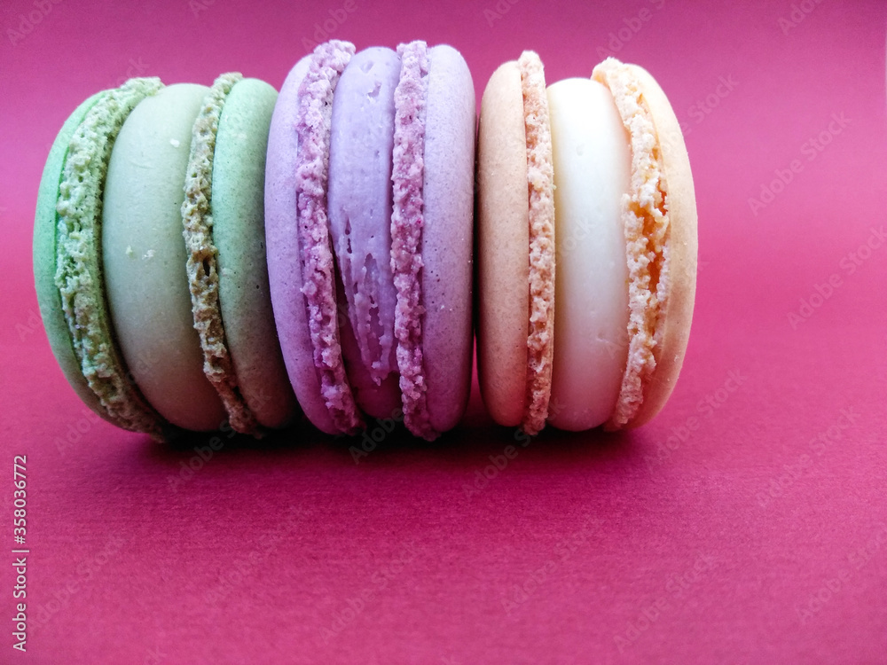 Beautiful tasty macaroon cakes lie on a bright pink background. Orange ...