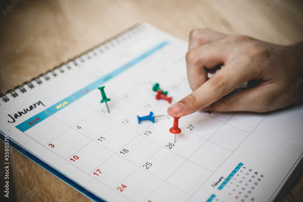 people's hand press red thumbtack on white calendar to marked important ...