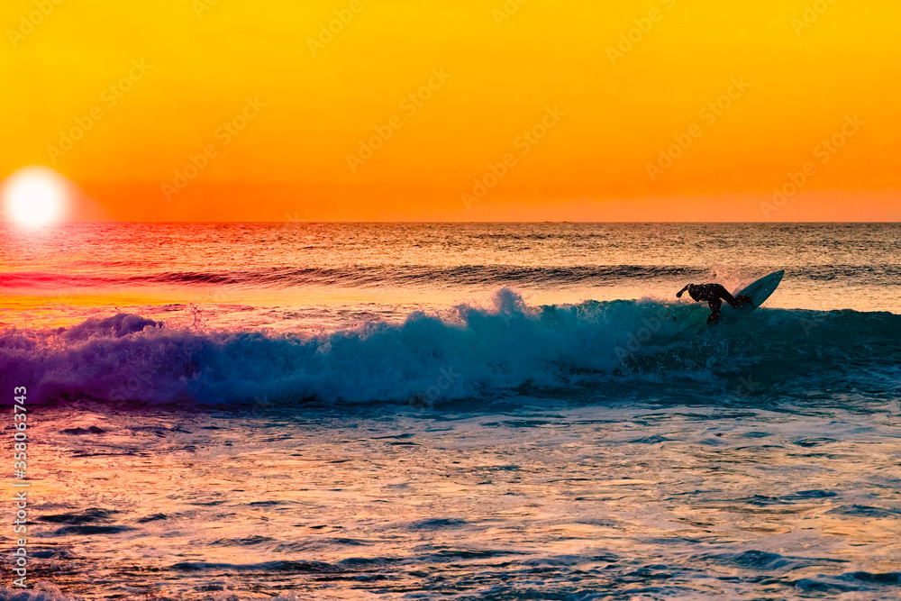 The silhouette of a surfer riding a wave at an empty surf spot. Young ...