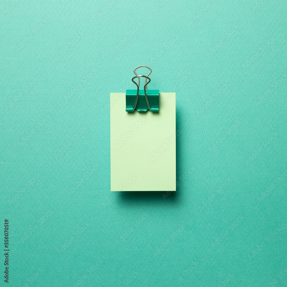 Green memo paper, sticky notes with green binder clip on mint green ...