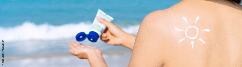Young Asian women with sun shape on the shoulder apply sun cream on to ...