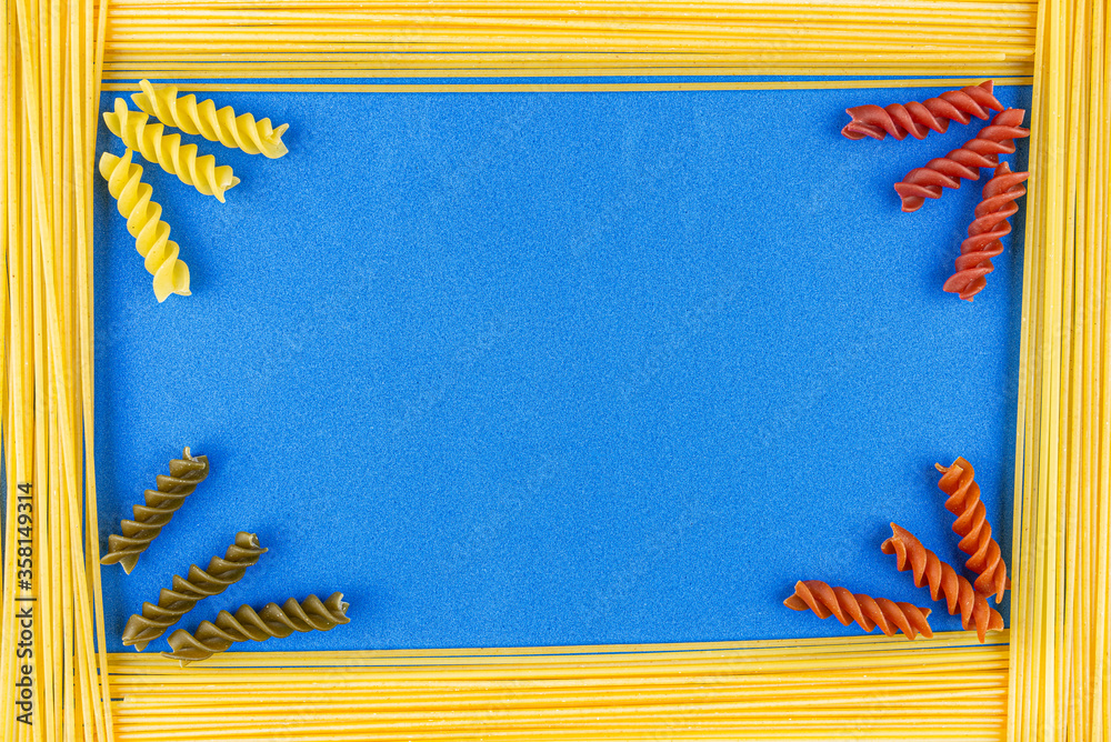 Frame made of spaghetti pasta on a blue foam background, colorful ...