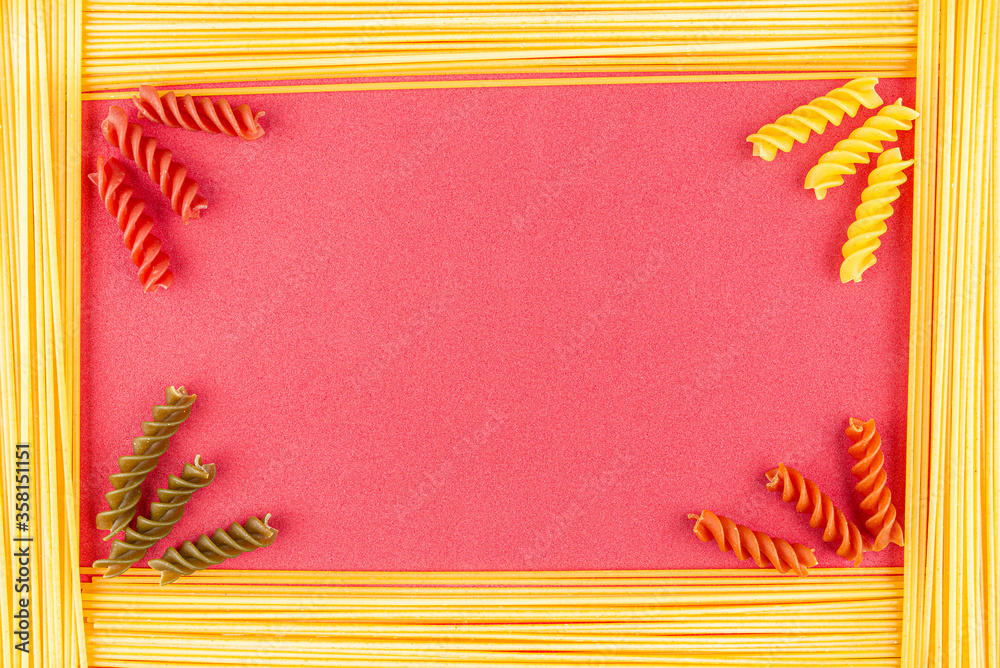 Frame made of spaghetti pasta on a red foam background, colorful spiral ...