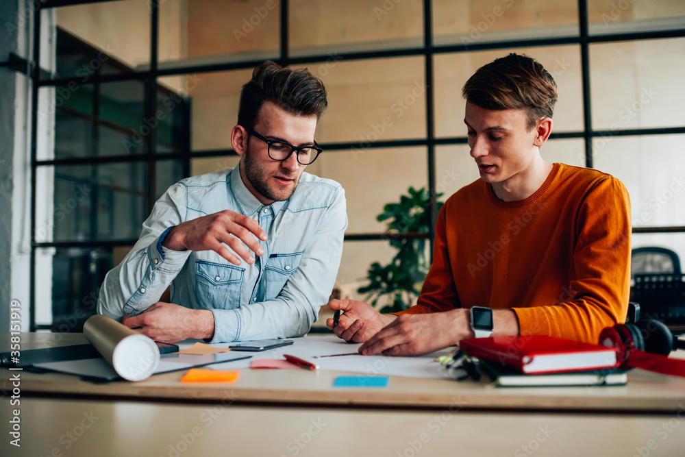 Skilled male colleagues drafting together discussing ideas for project ...