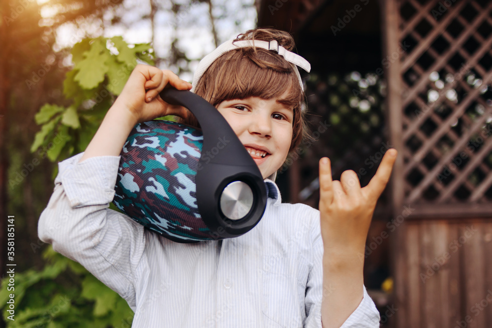 Child with portable speaker enjoying the music in park, outdoors. Kid ...