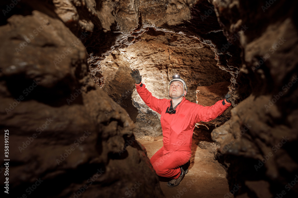 Man walking and exploring dark cave with light headlamp underground ...