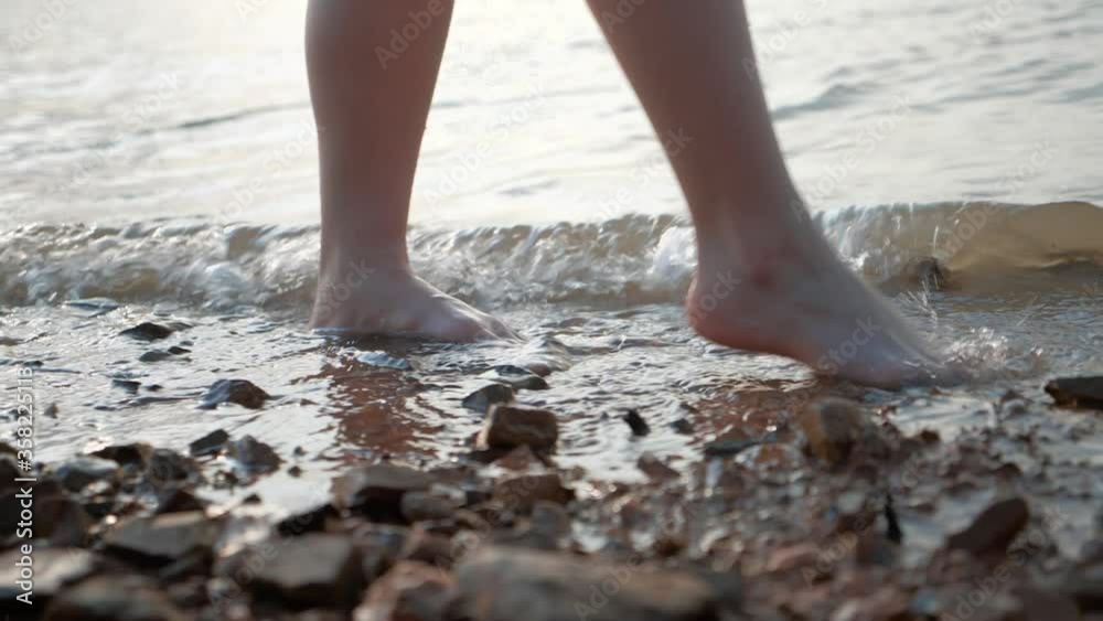 Close Up Of Female Feet Walking On Pebble Sand At The Beach With Ocean