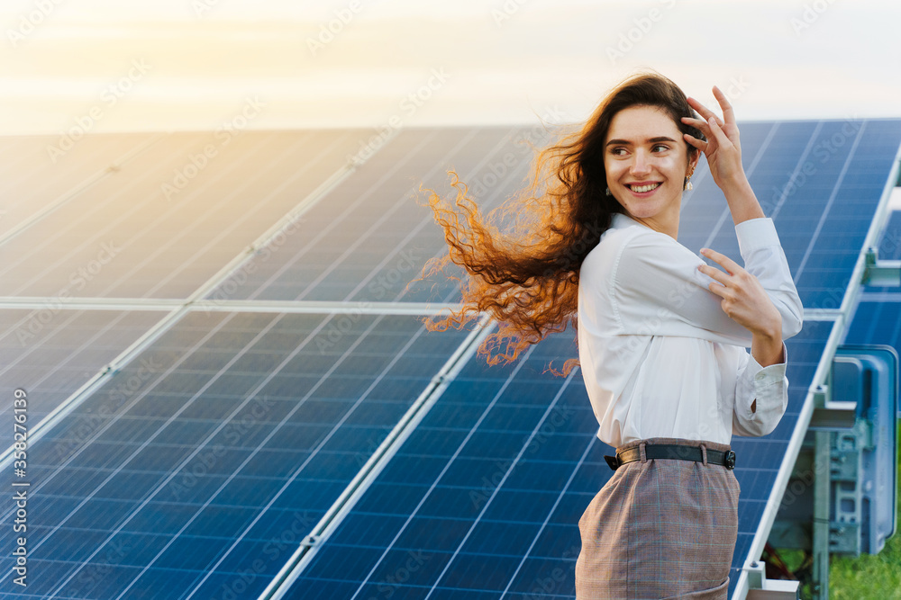 Model with solar panels stands in row on the ground at sunset. Girl ...