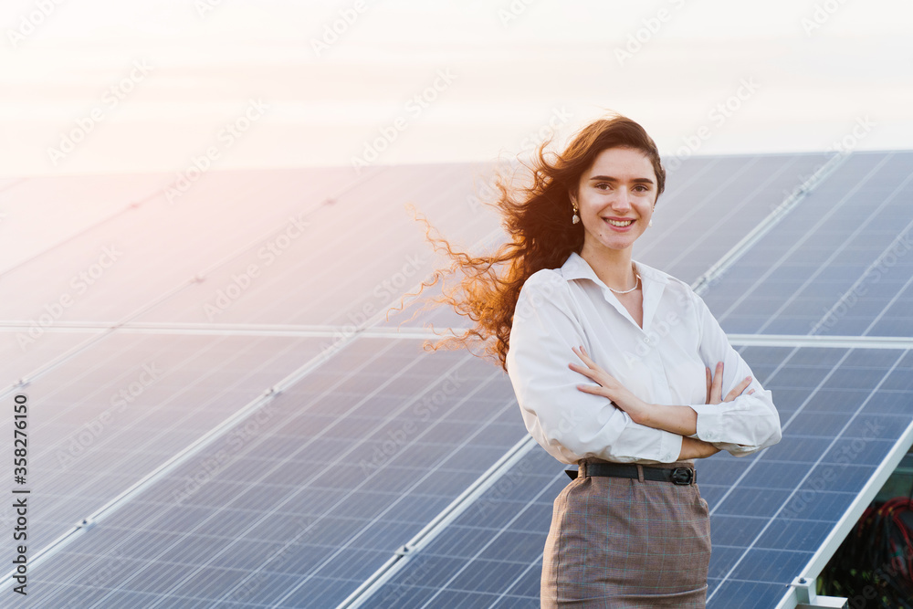 Model with solar panels stands in row on the ground at sunset. Girl ...