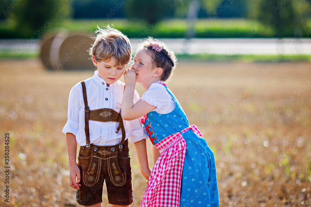 Two kids in traditional Bavarian costumes in wheat field. German ...