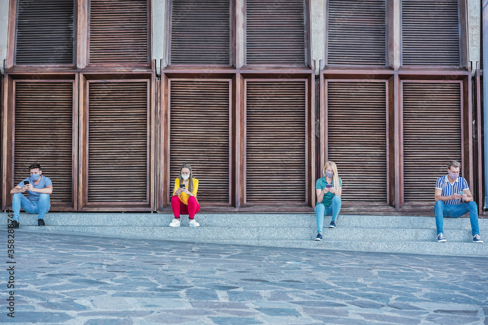 Young people wearing face safety masks using smart mobile phones while ...