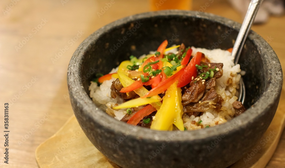 Bulgogi (Korean dish of grilled beef) on rice in a stone bowl in a ...
