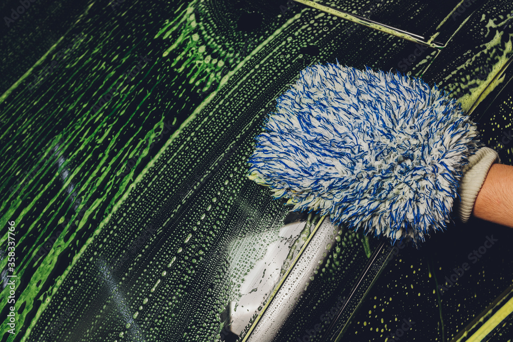 Car wash by hand. Soap suds, bubbles and mitt. Man washing a car by ...