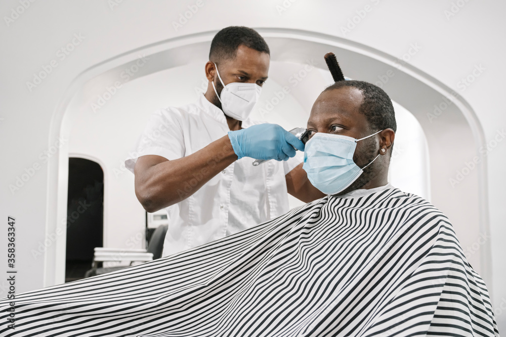 Barber wearing surgical mask and gloves cutting hair of customer Stock ...