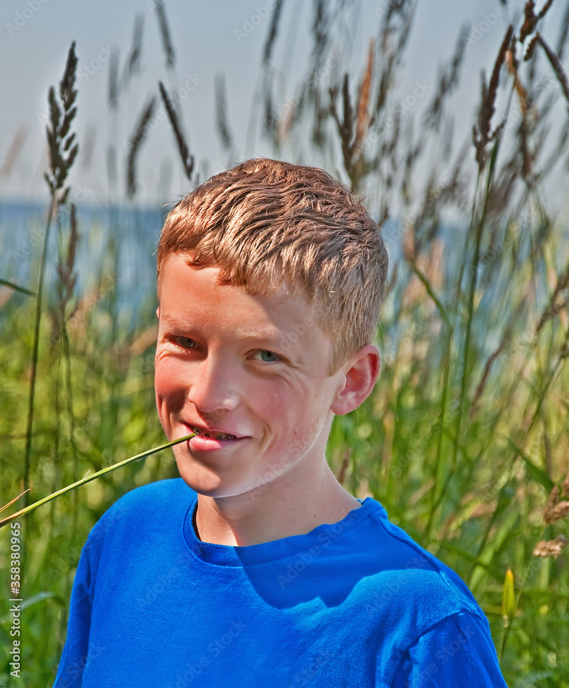 This cute Caucasian 13 year old boy is outdoors with a stem of long ...