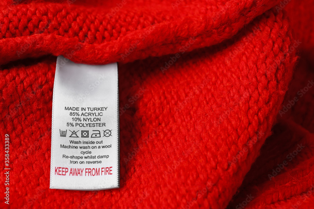 Clothing label with care symbols and material content on red sweater ...