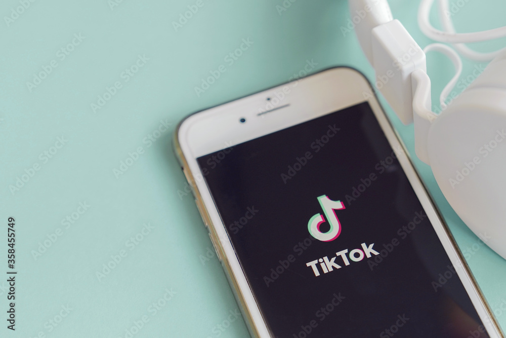 smartphone with Tik Tok app on screen and white headphone on blue ...
