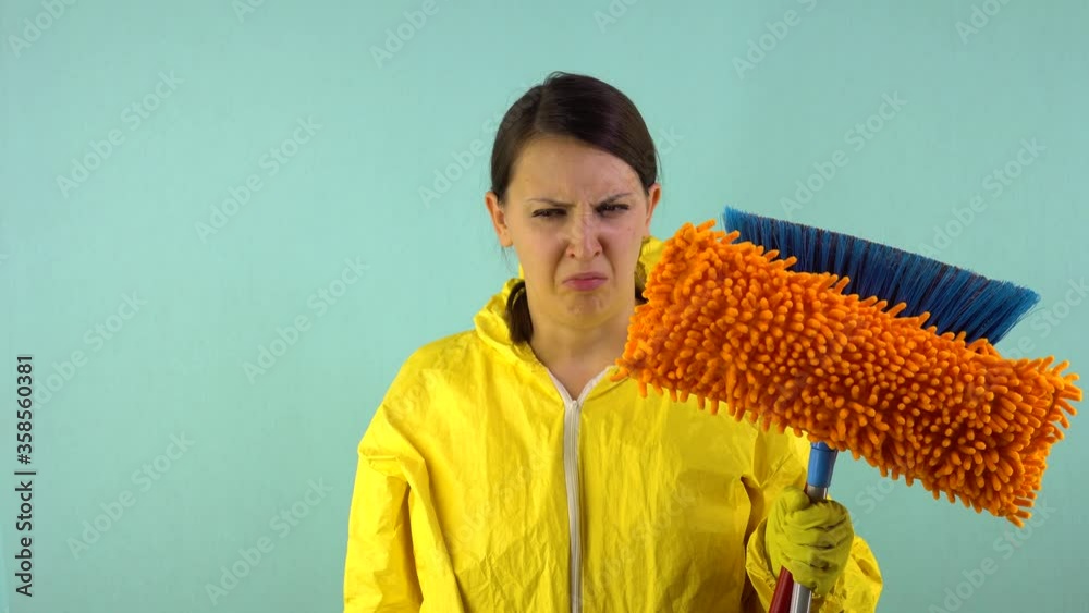 Sad and tired cleaning lady in a yellow suit on a blue background. The ...