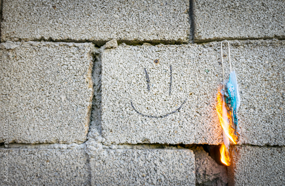 Medical face mask is hanging and burning with smiley face shown on the ...