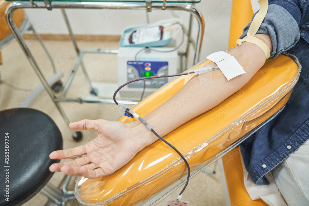 Crop anonymous female volunteer giving blood for save life in modern ...