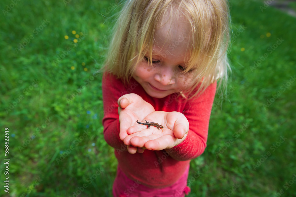little girl holding and exploring lizard in nature Stock Photo | Adobe ...