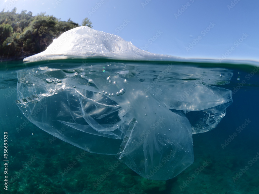 world in plastic bag drifting underwater representing ocean pollution ...