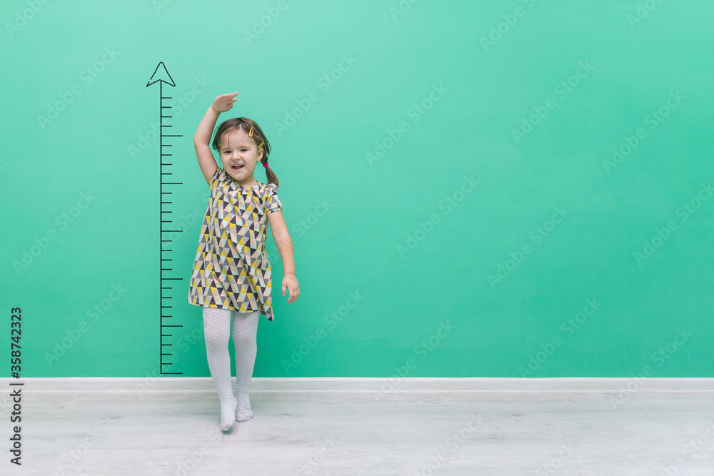 Kid is measuring the growth. The girl on the background of a hand-drawn ...