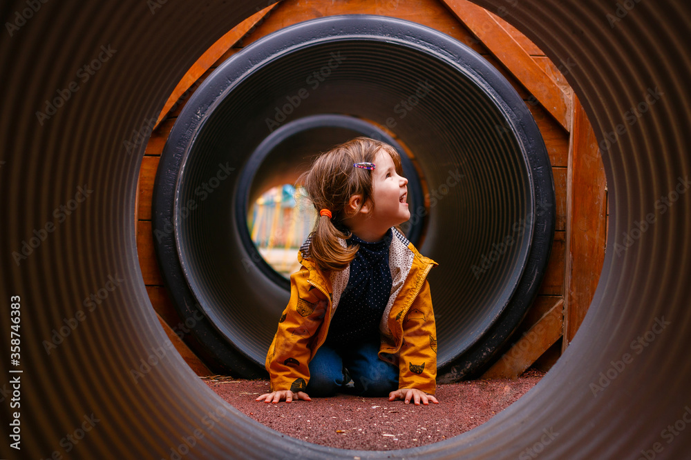 A little girl climbs in the pipes. Modern and safe children's ...