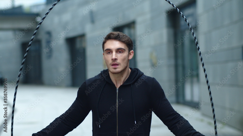Fitness man jumping on skip rope outdoor. Closeup sportsman using jump ...