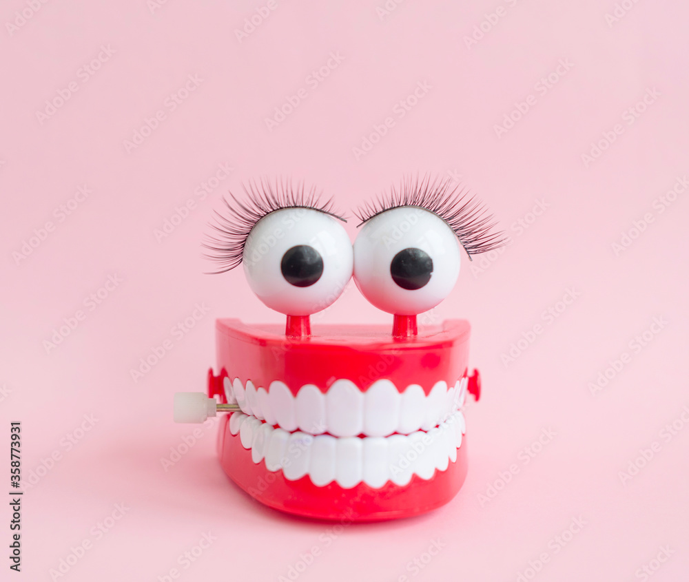 toy with smiling teeth and eyes on pink background as a concept of ...
