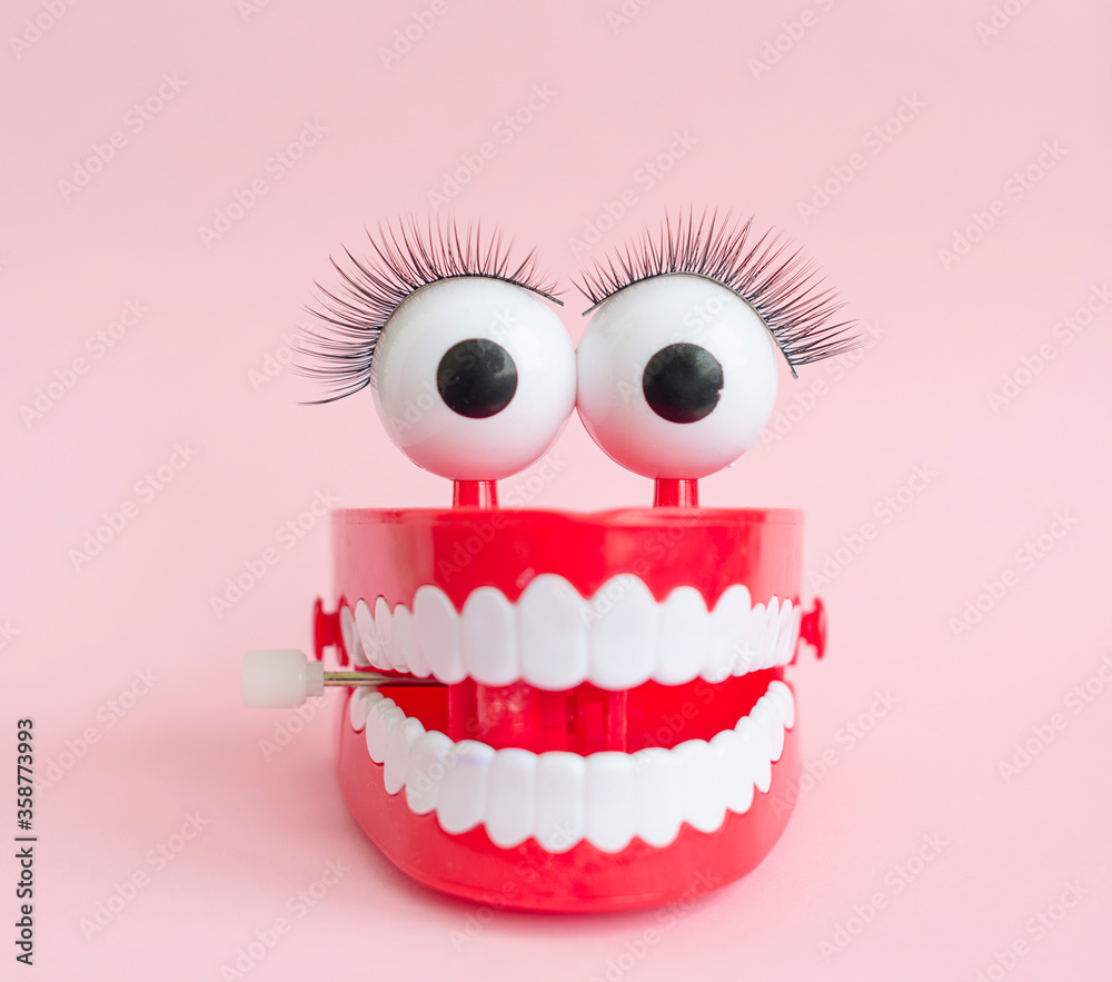 toy with smiling teeth and eyes on pink background as a concept of ...