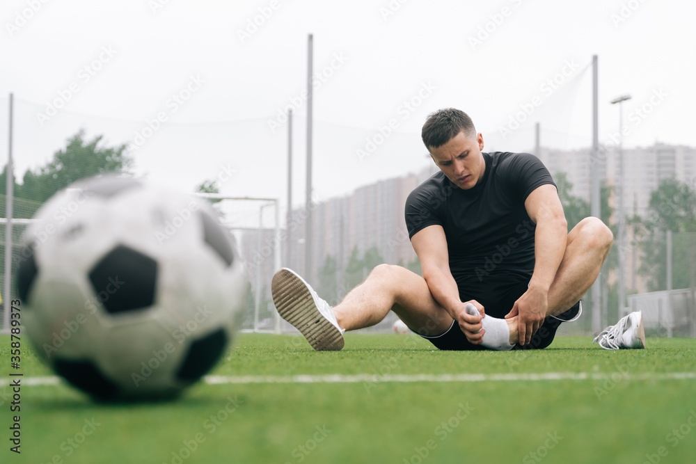 soccer player A man holds his foot. focus on the soccer ball ...