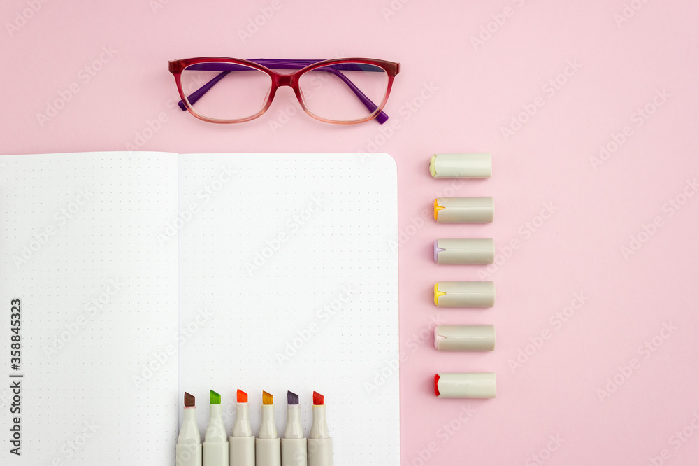 Open bullet journal, glasses and multi-colored markers on pink ...