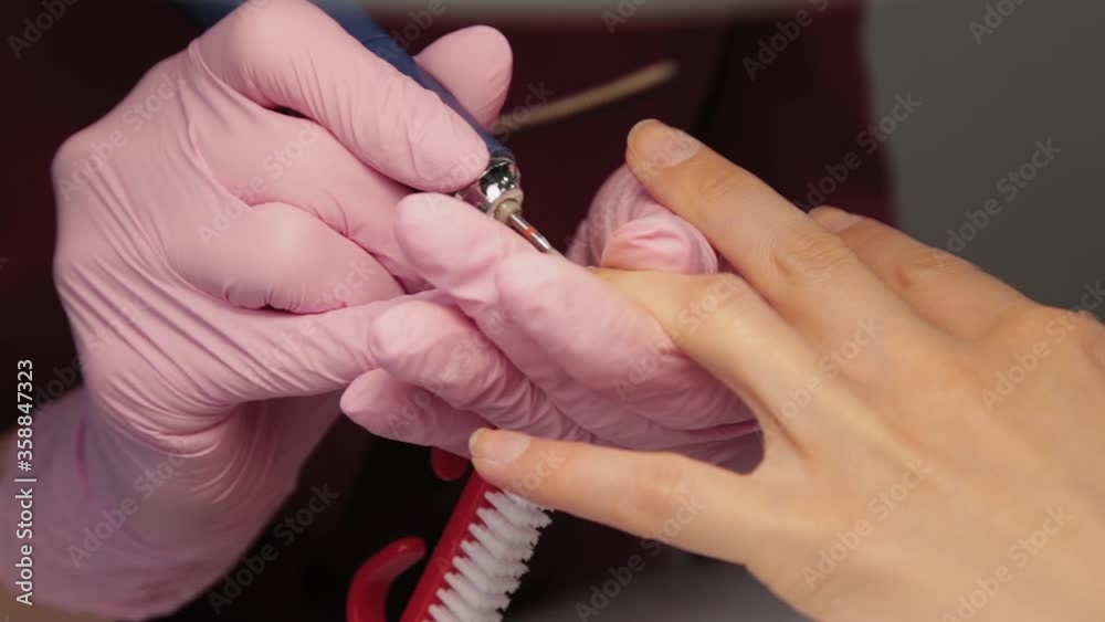 Manicurist cuts nails with a machine to a client in a manicure salon ...