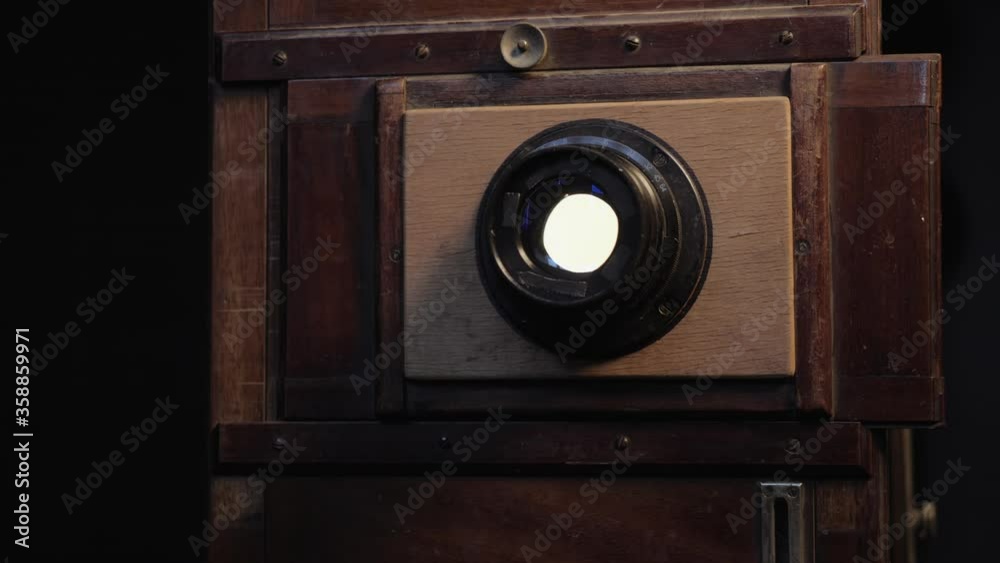 Close-up view of luminous lens of outdated rare wooden accordion camera ...