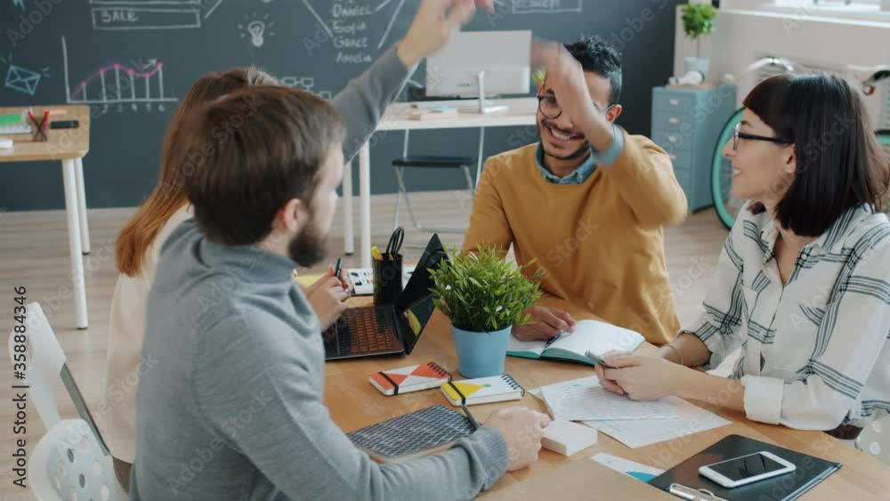 Male and female coworkers are doing high-five sharing ideas working ...
