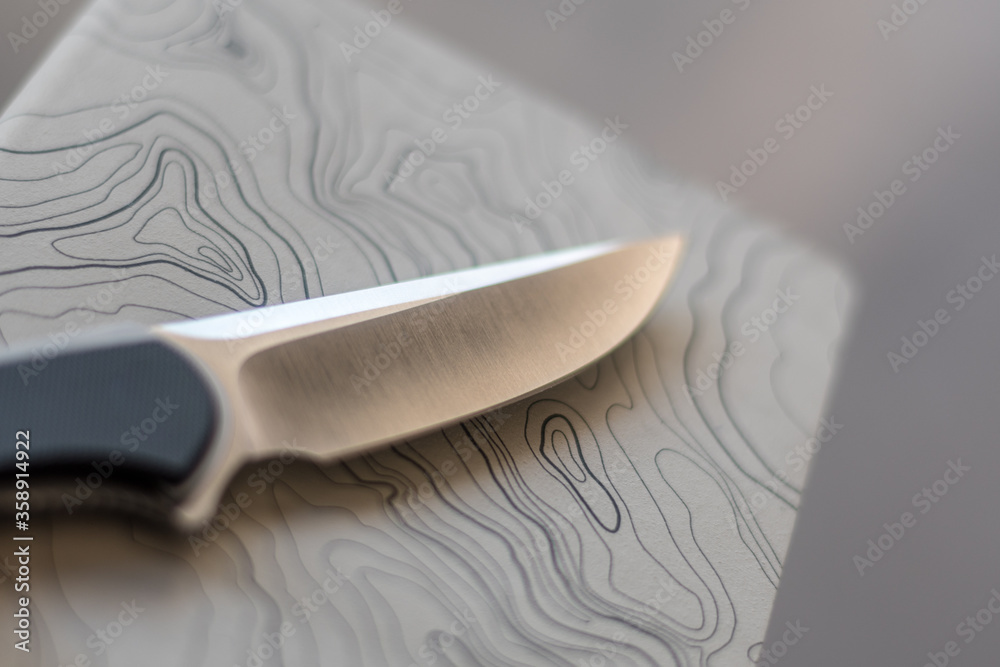 Isolated close up of a single blade knife on a topographic map notebook ...