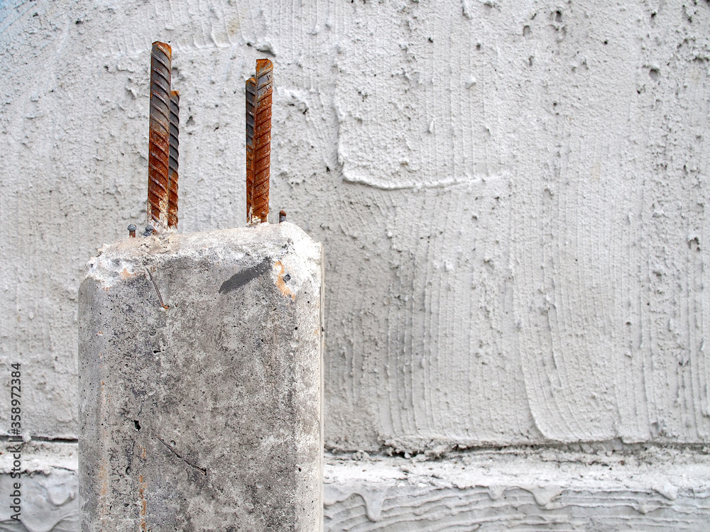 single concrete column with rusty steel rebars and gray rough cement ...