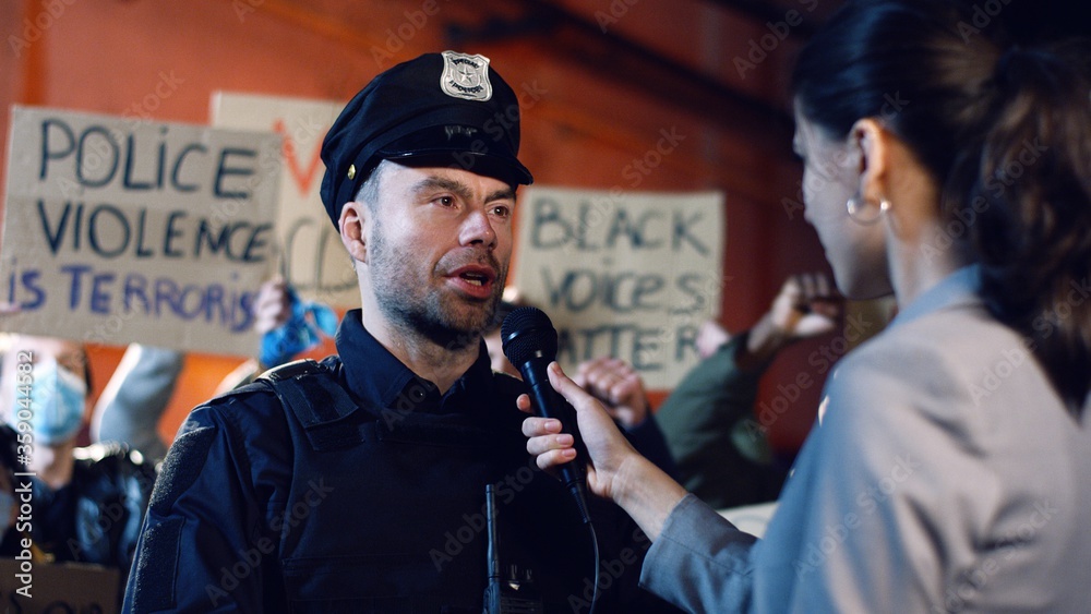 Caucasian female correspondent interviewing policeman at street at ...