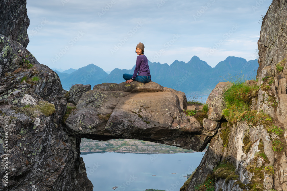 Young happy Asian woman sitting on Djevelporten or Devil's gate in ...