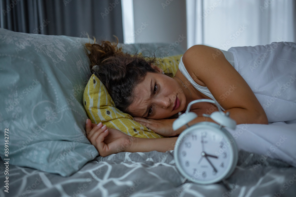 Photo of a young woman lying in bed at night, wide awake with a case of ...