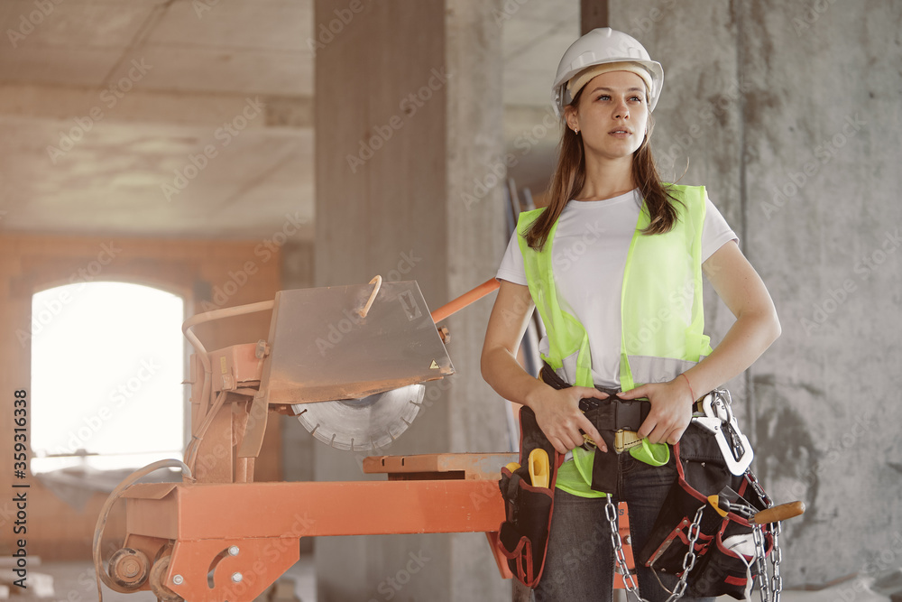 Construction worker girl with safety belt and tool bag on construction ...