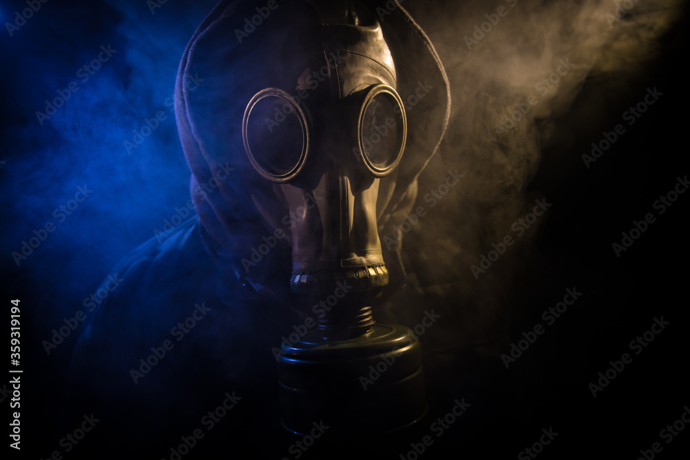Gas mask with clouds of smoke on a dark background. Sign of radioactive ...