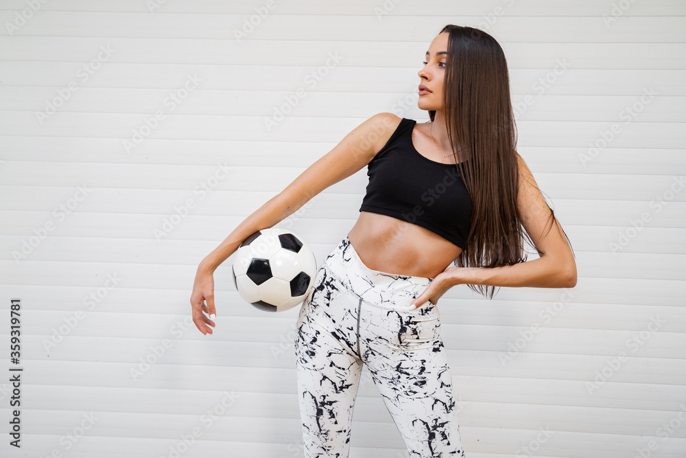 Attractive beautiful fitness model with soccer ball white garage door ...