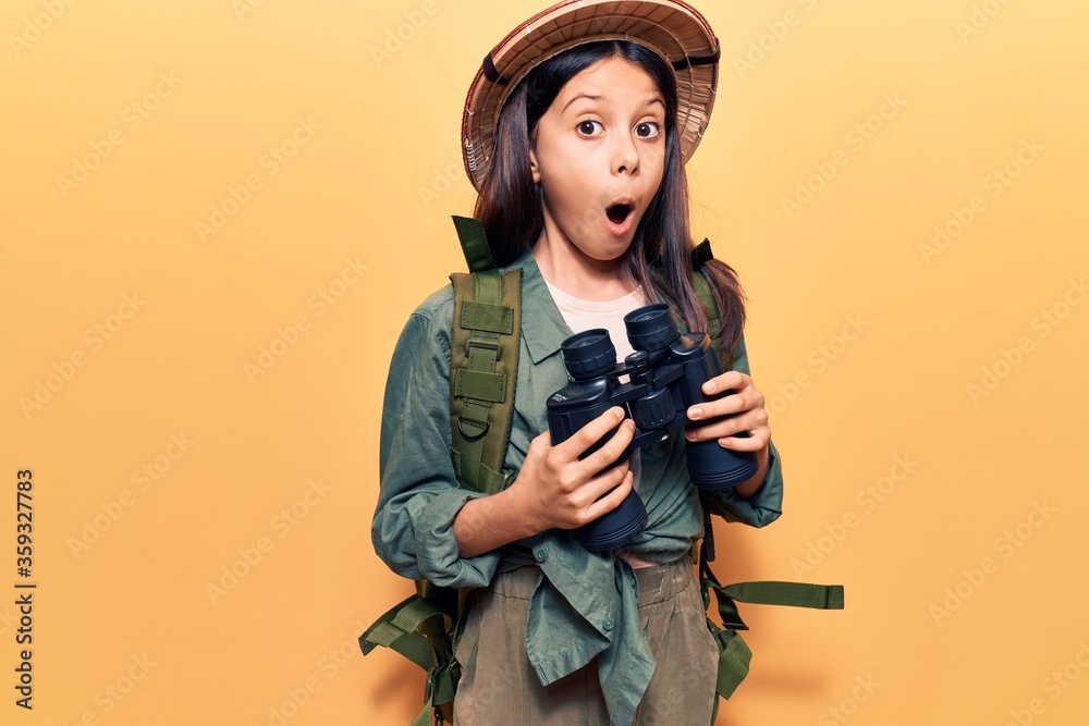 Beautiful child girl wearing explorer hat holding binoculars scared and ...