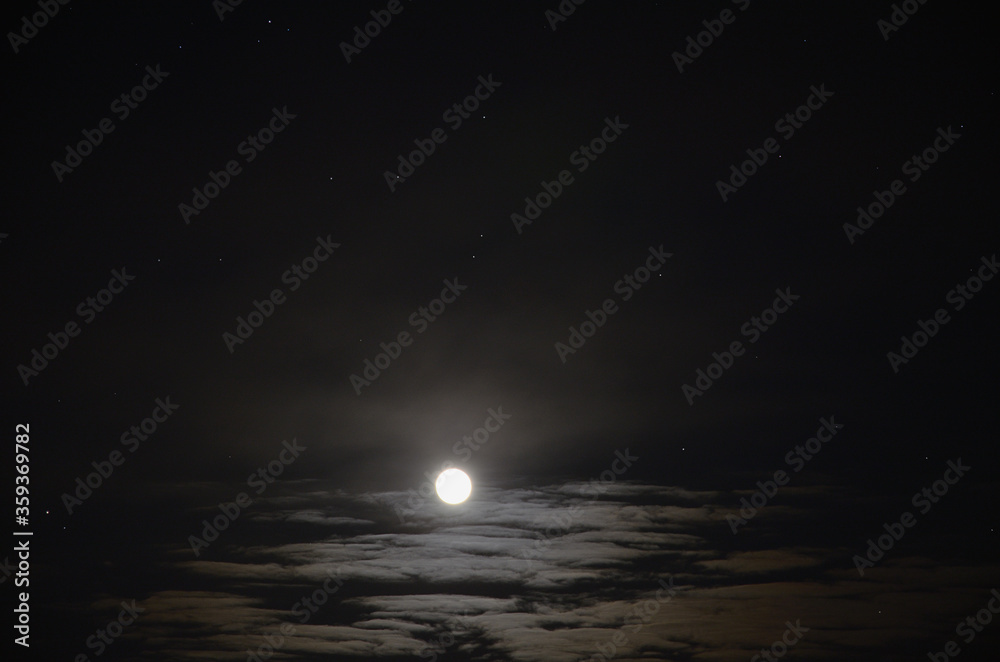Black background of the night sky. A white fuzzy moon and some bright ...