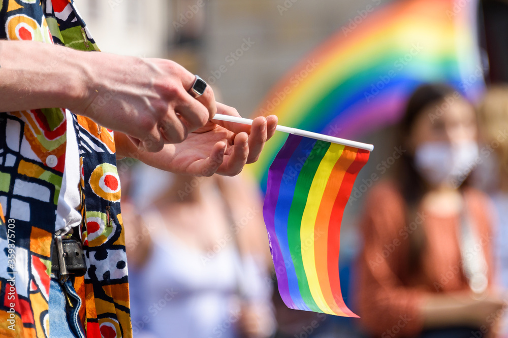human hand hold LGBT paper flag. LGBT rainbow flag on foreground as a ...