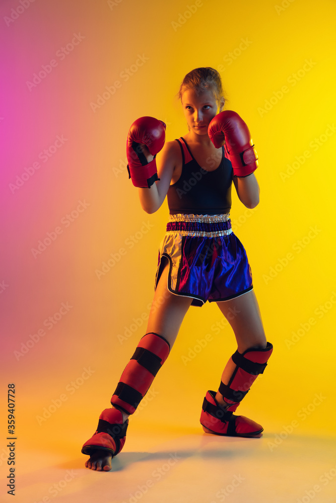 Little caucasian girl, kick boxer on gradient background in neon light ...