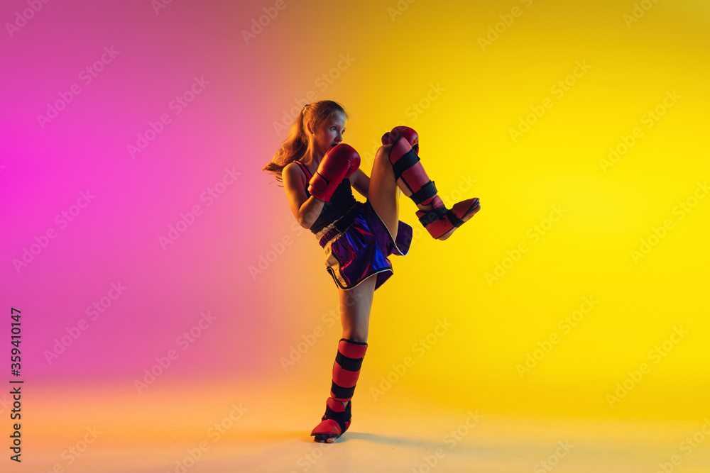 Little caucasian girl, kick boxer on gradient background in neon light ...