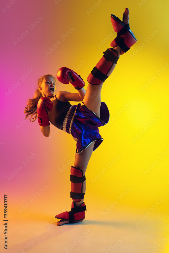 Little caucasian girl, kick boxer on gradient background in neon light ...